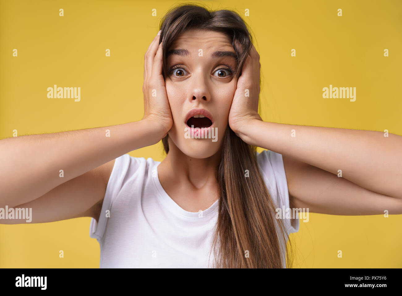 Portrait of shocked scared young woman in casual white shirt hearing ...