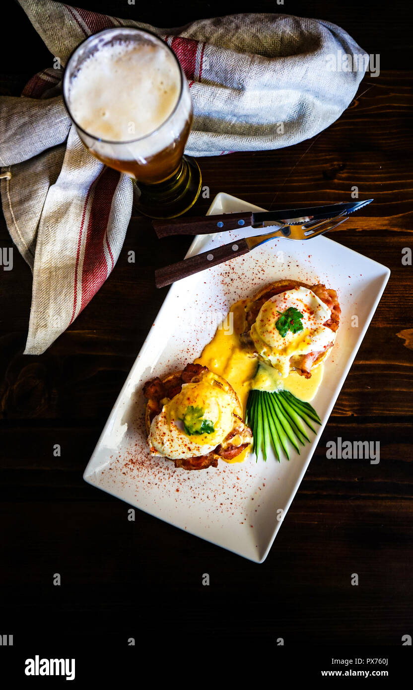 Rustic lunch set with benedict eggs and cucumber salad on dark wooden ...