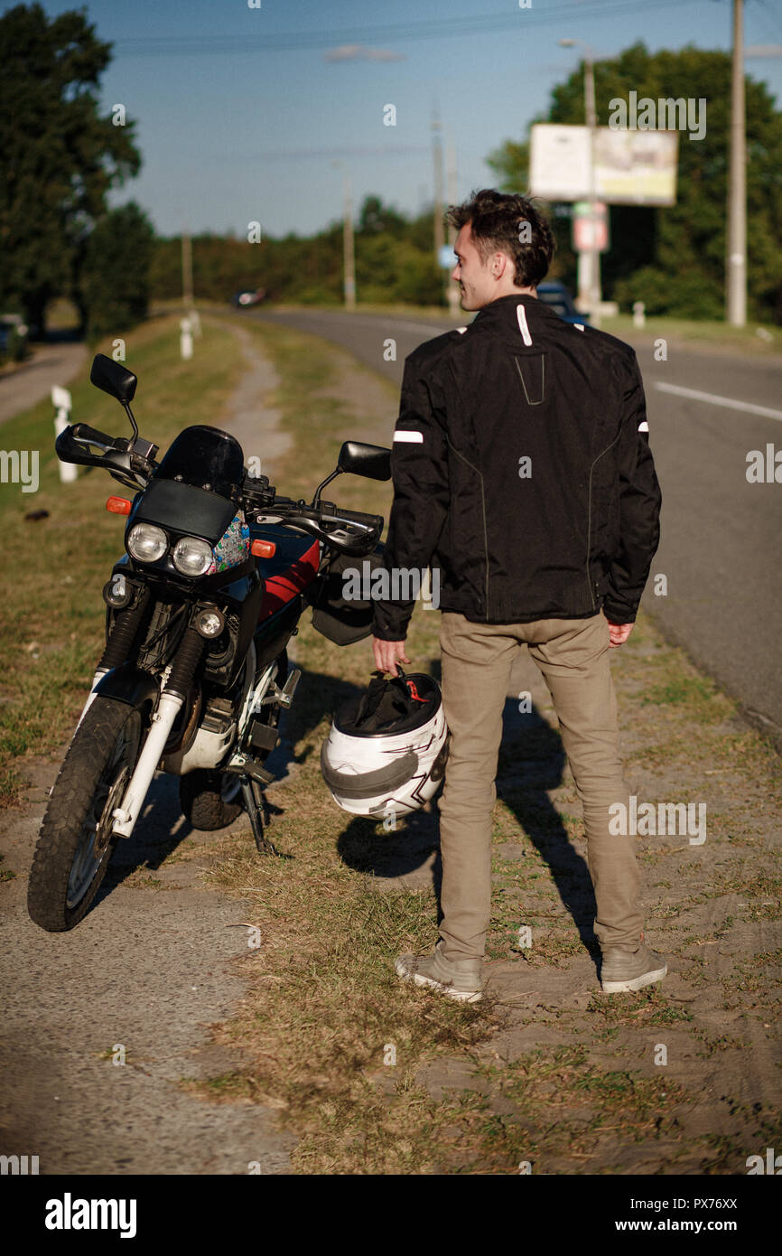 Shot of the biker's back, standing near his motorbike Stock Photo - Alamy