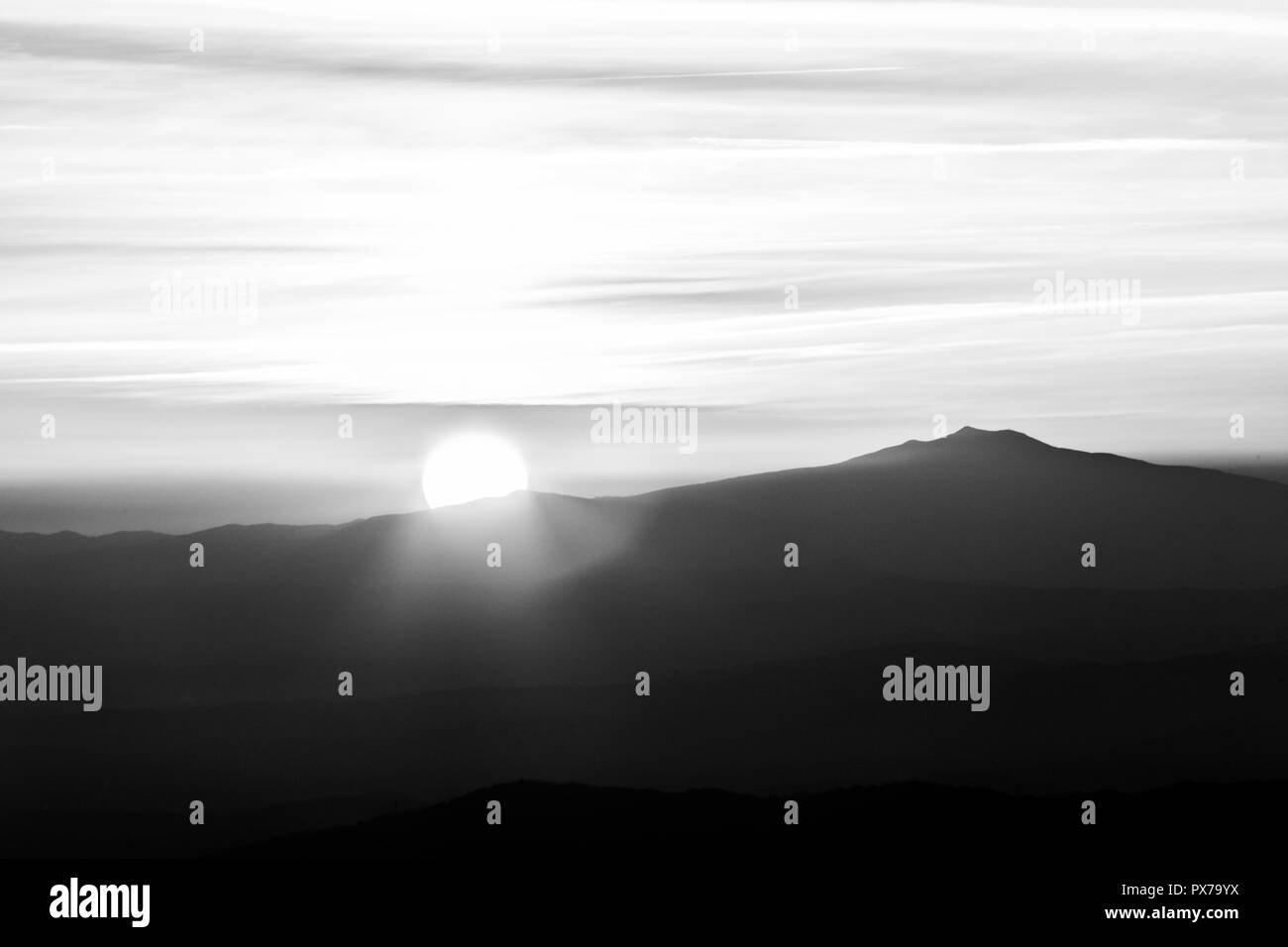Beautiful sunset with sun coming down behind various layers of ...