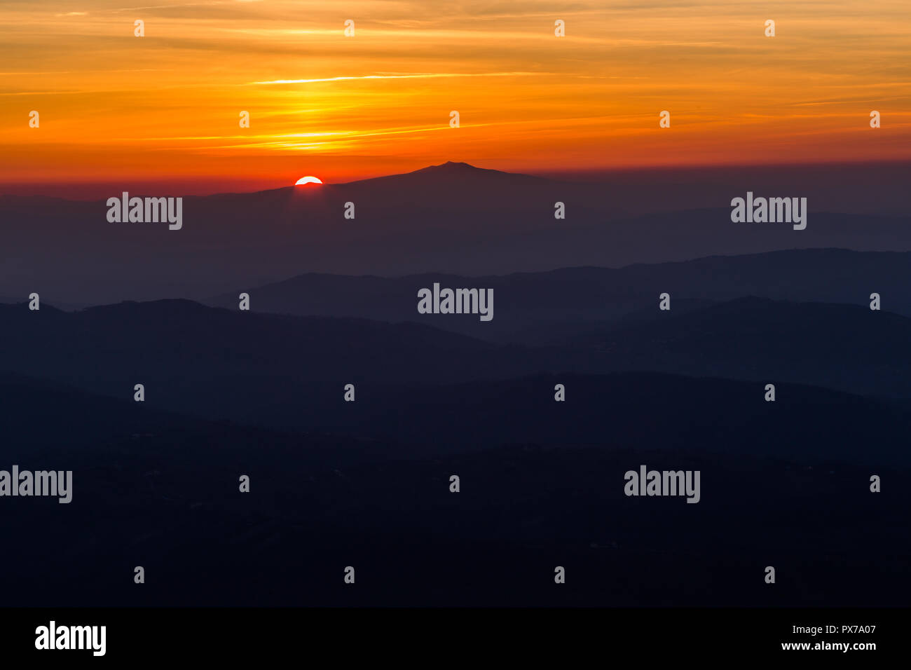 Beautiful sunset with sun coming down behind various layers of ...