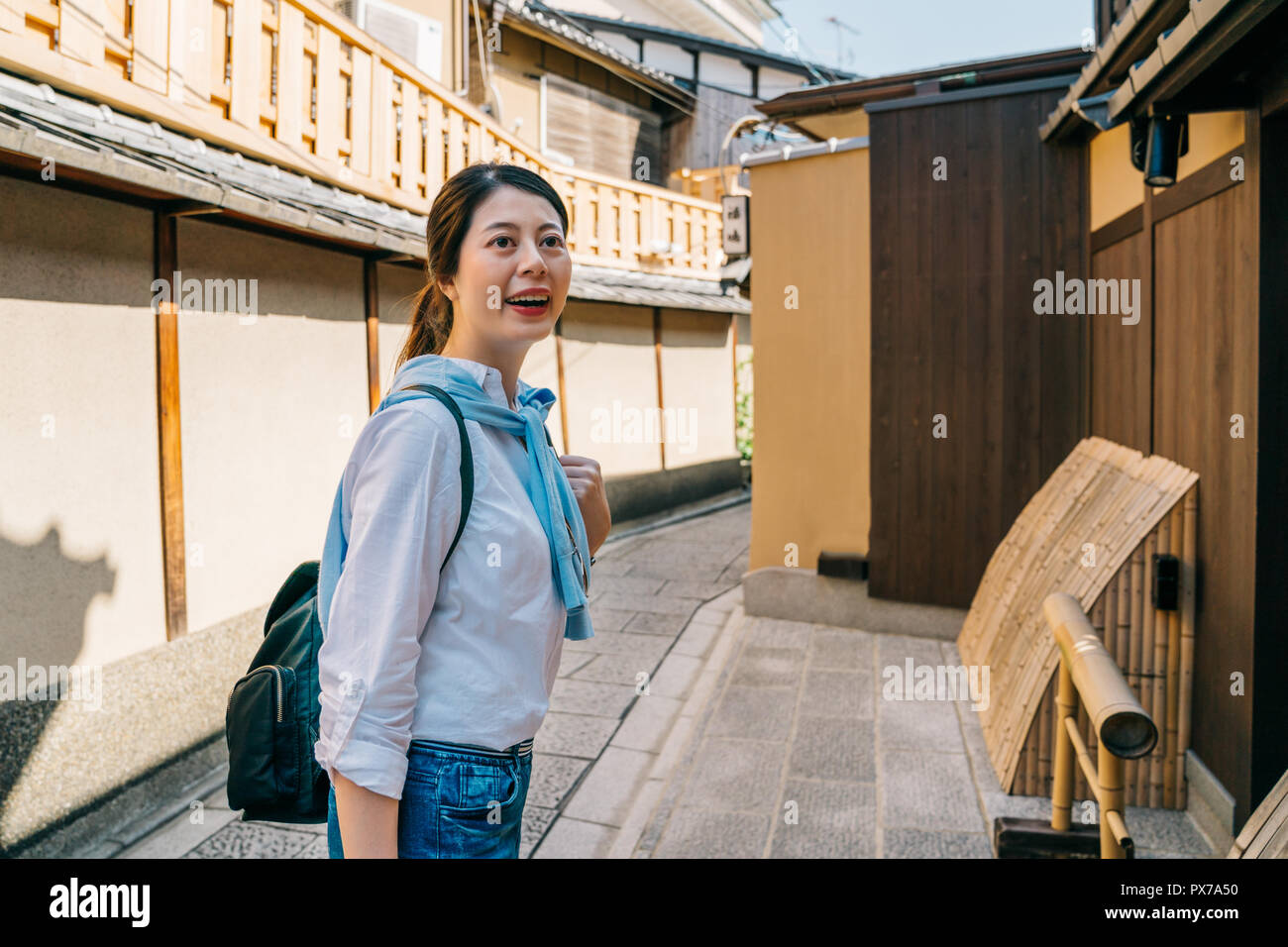 young backpacker walking in the alley with Japanese wooden building ...