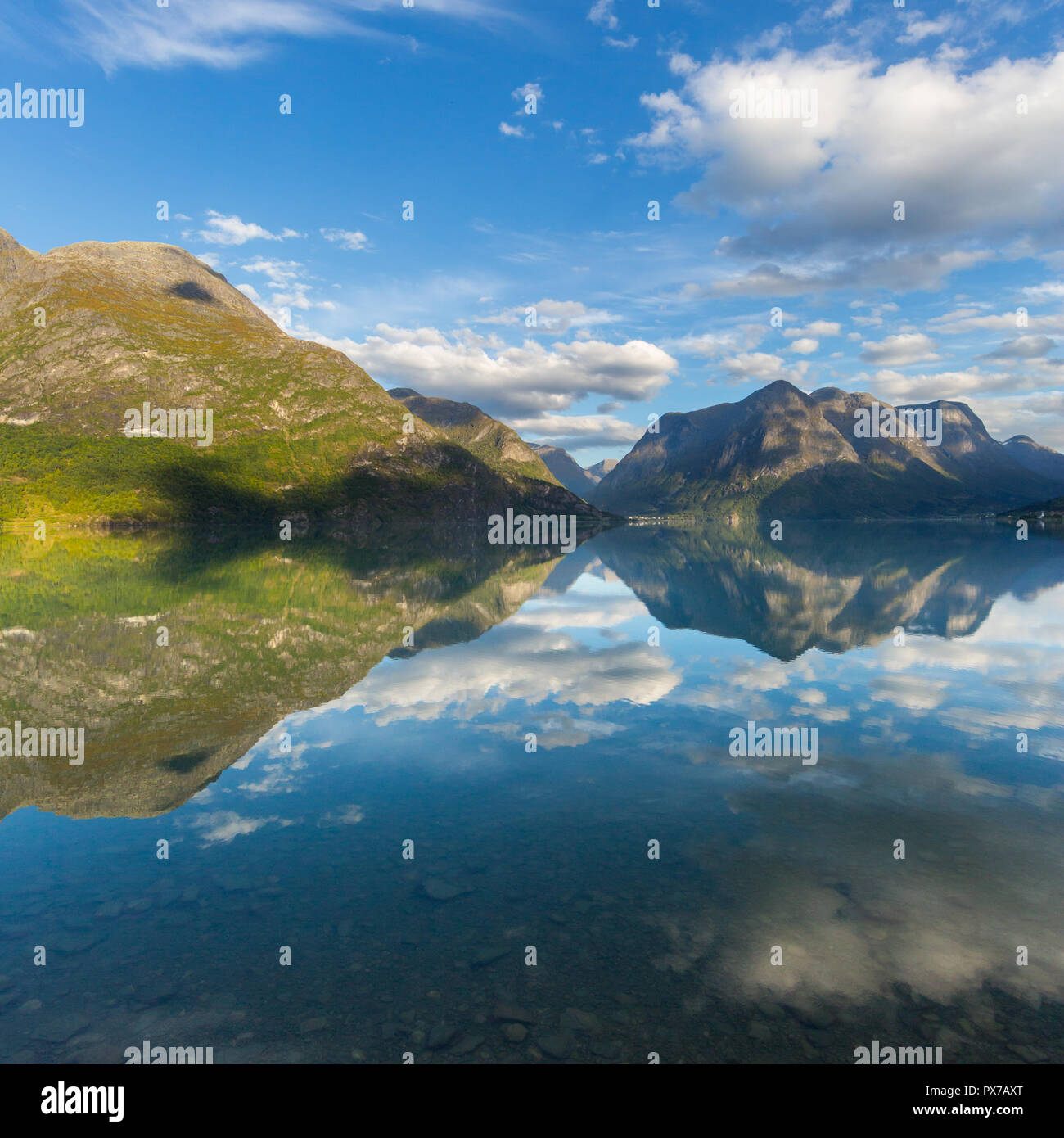 natural mountains mirrored in Geiranger fjord, blue sky, clouds Stock ...