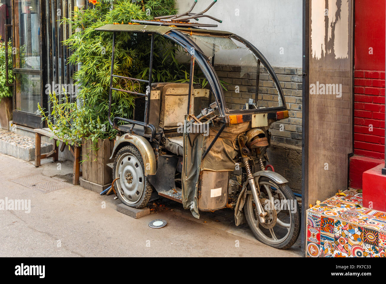 A rusty and old motorized rickshaw in a back alley in a Beijing hutong ...