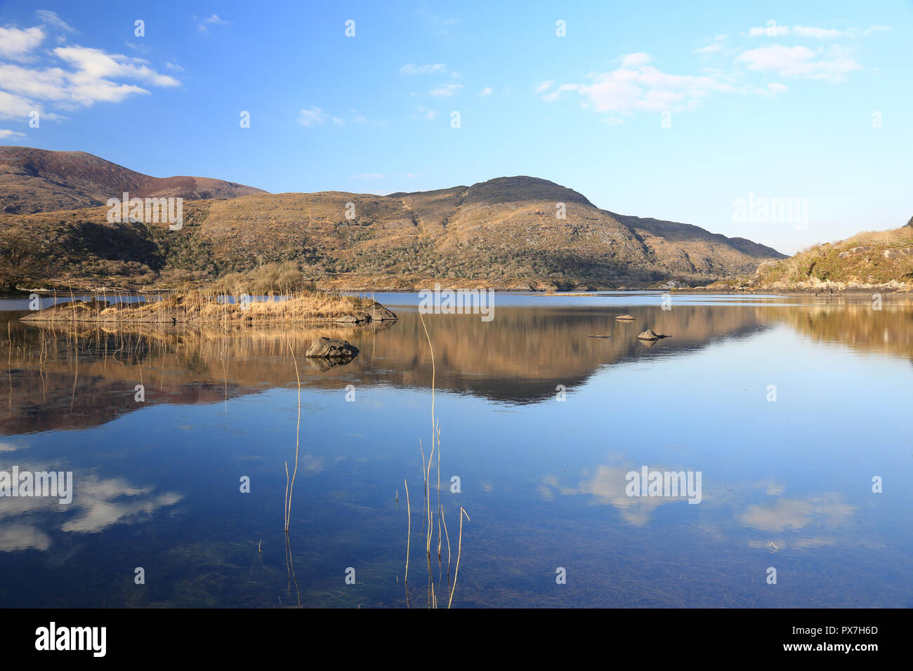 calm lake waters reflecting the surrounding hills, ring of kerry ...