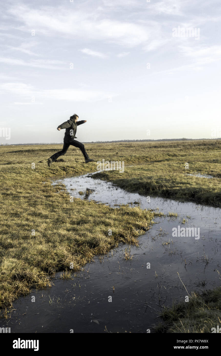 Man jumping over the river, Austria, Burgenland, Neusiedlersee ...