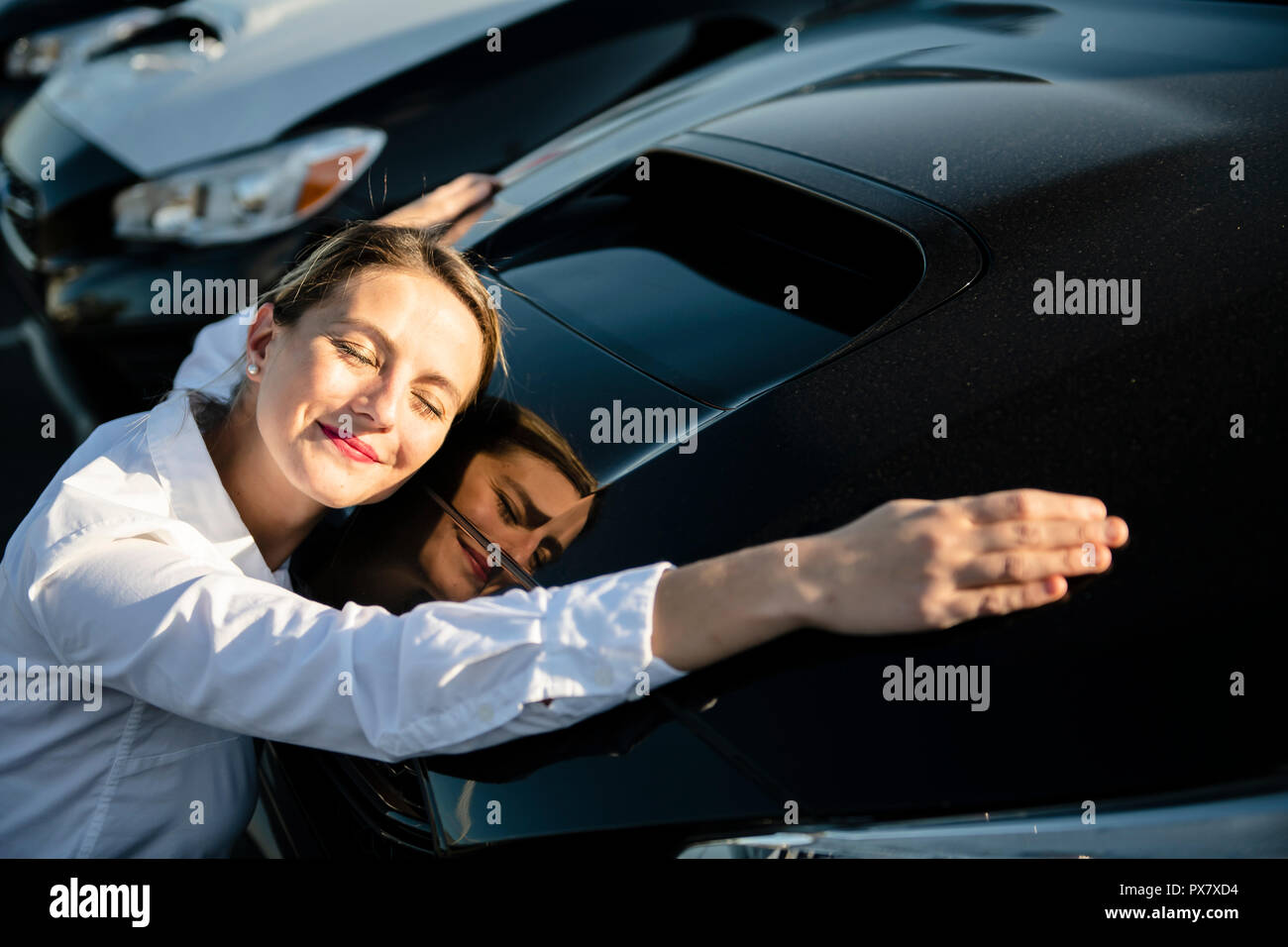 A Car seller woman hugging car at the garage Stock Photo - Alamy