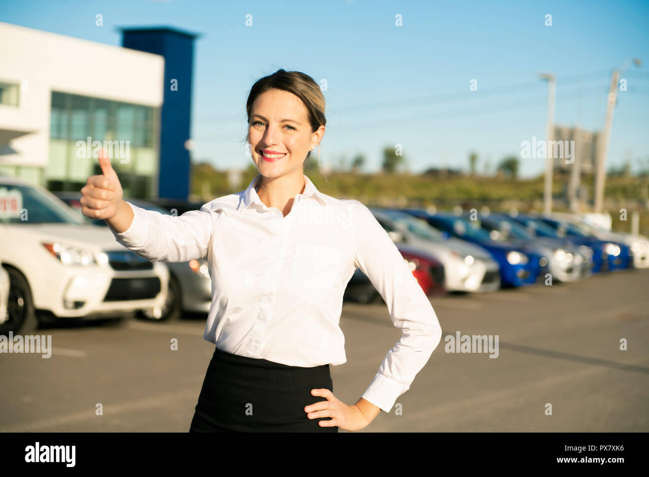 A Young woman car rental in front of garage with cars on the background ...