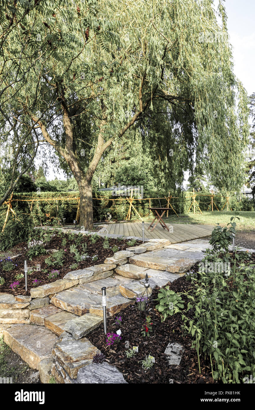 Nature garden with stone wall and wooden terrace Stock Photo - Alamy