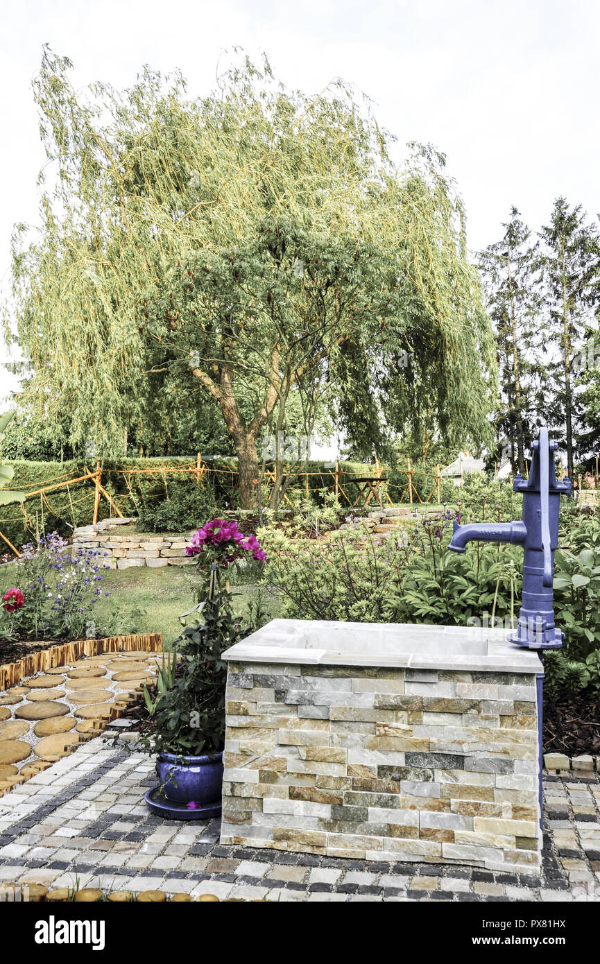 Nature garden with stone wall and wooden terrace Stock Photo - Alamy