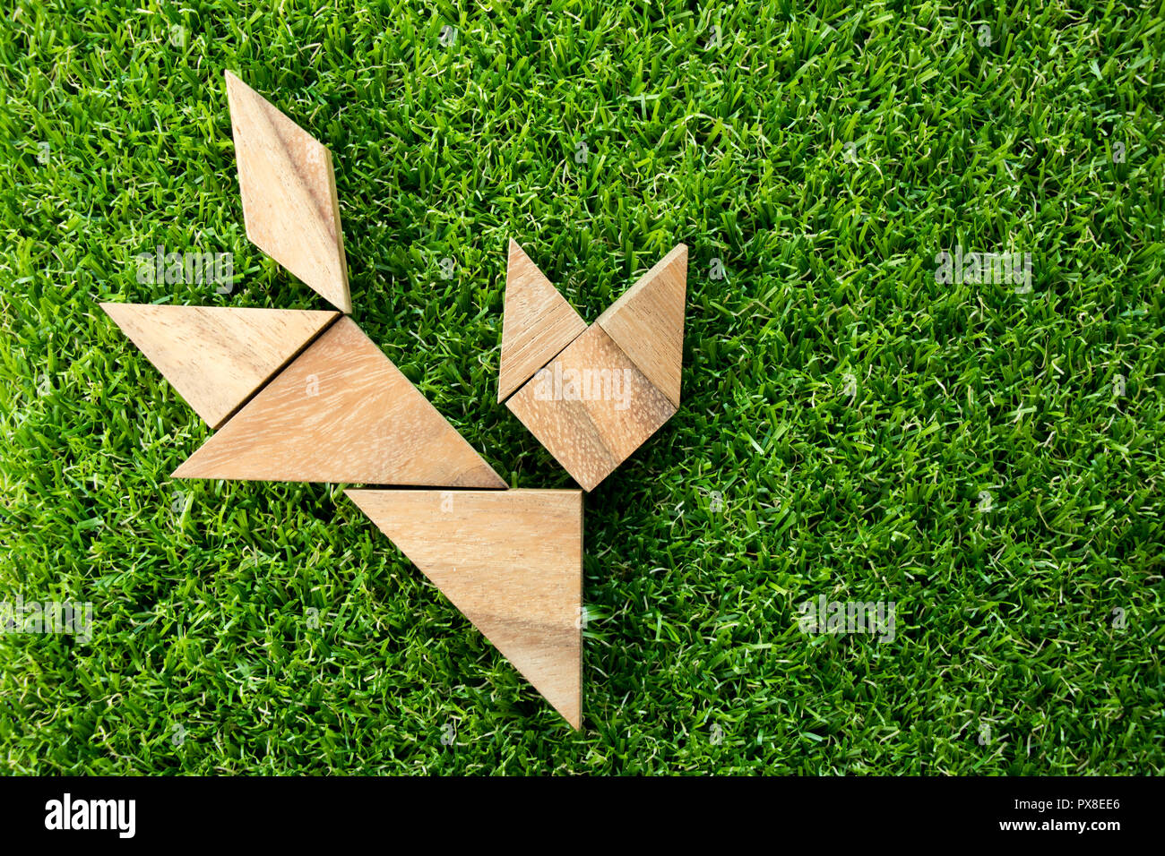 Wooden tangram puzzle in cat shape on artificial green grass background ...