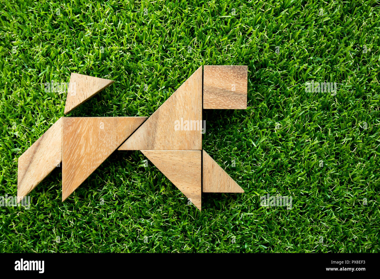 Wooden tangram puzzle in dog shape on artificial green grass background ...