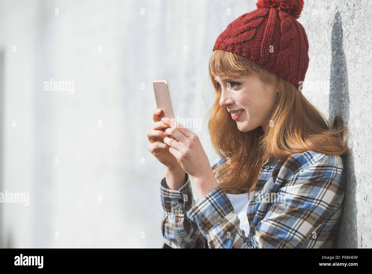 close up of a modern hipster woman with red hair that is using an ...