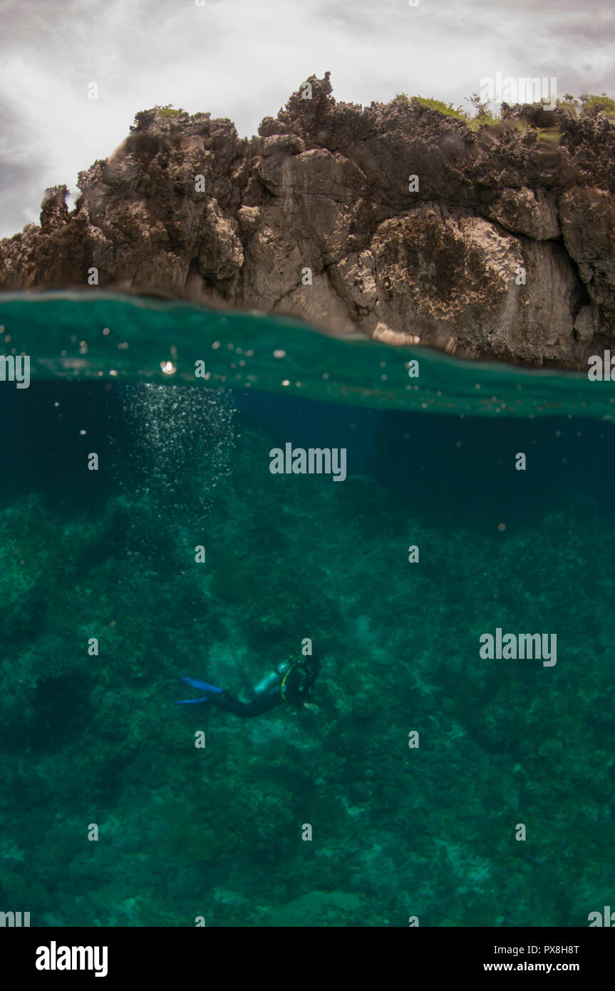 Diver diving by island, Boo Windows dive site, Boo Island, Misool, Raja ...