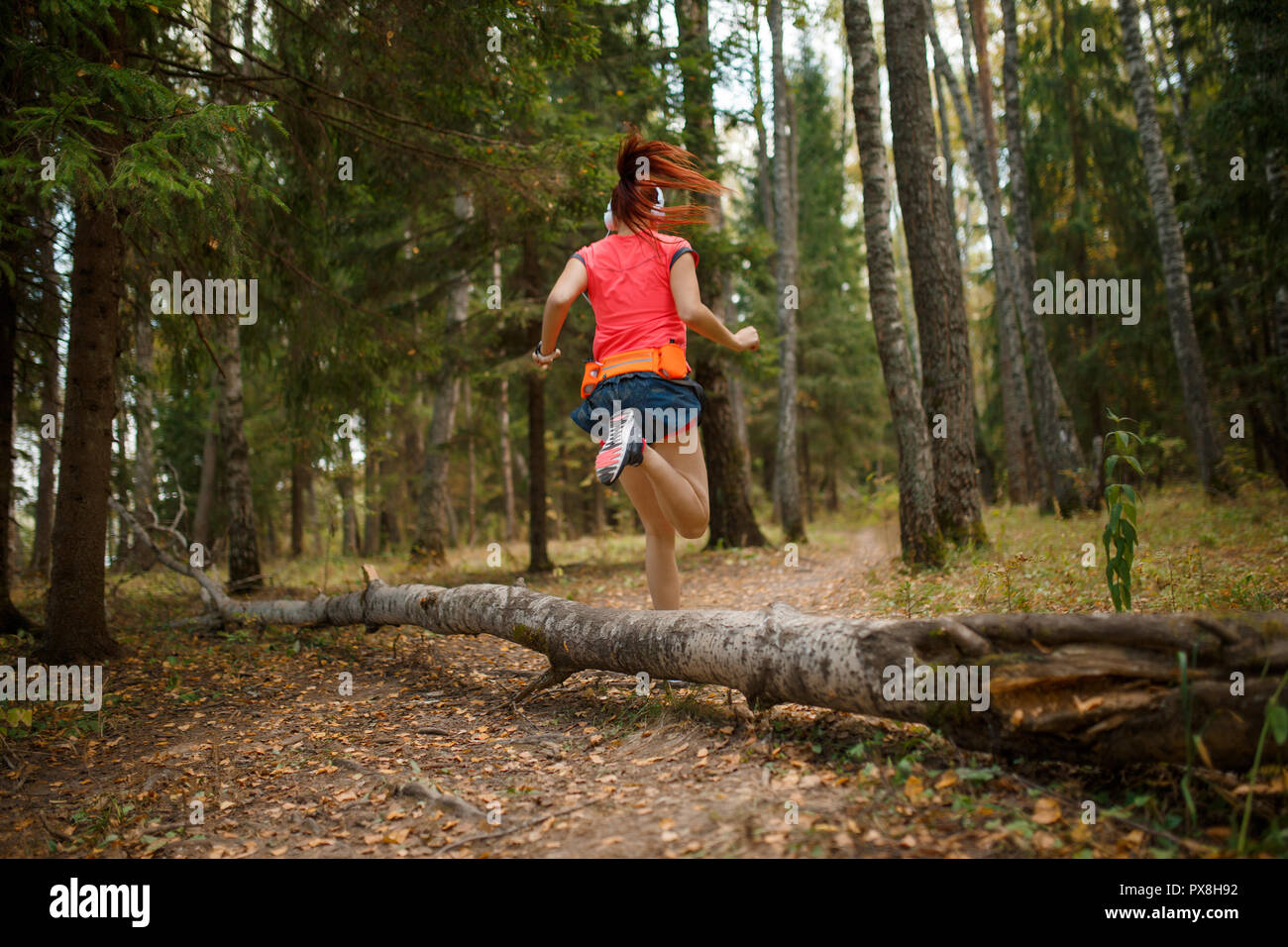 Photo from back of young woman running through forest Stock Photo - Alamy