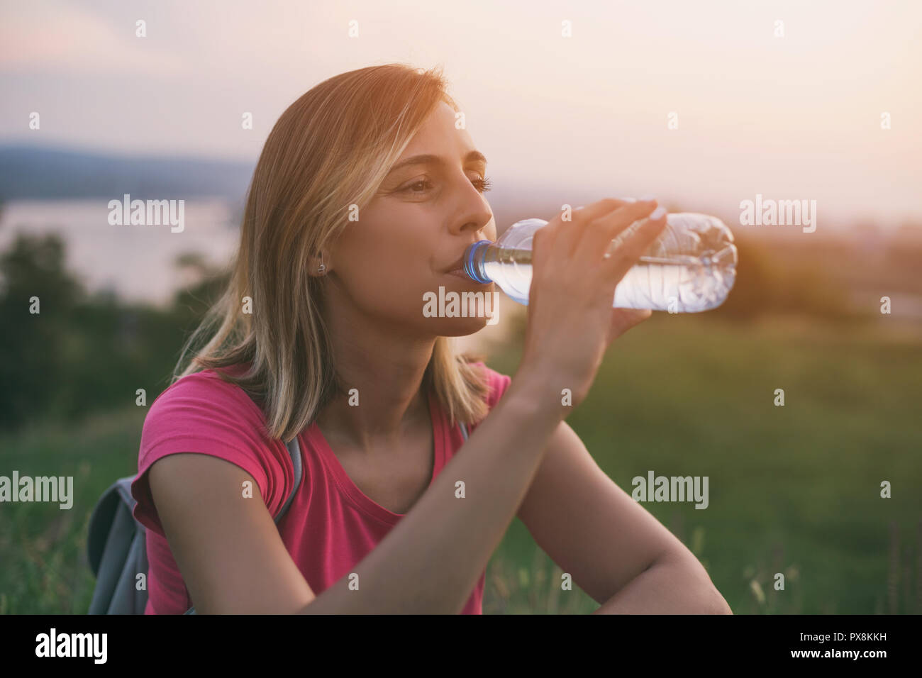 Beautiful woman enjoys drinking water outdoor with a cityscape and ...