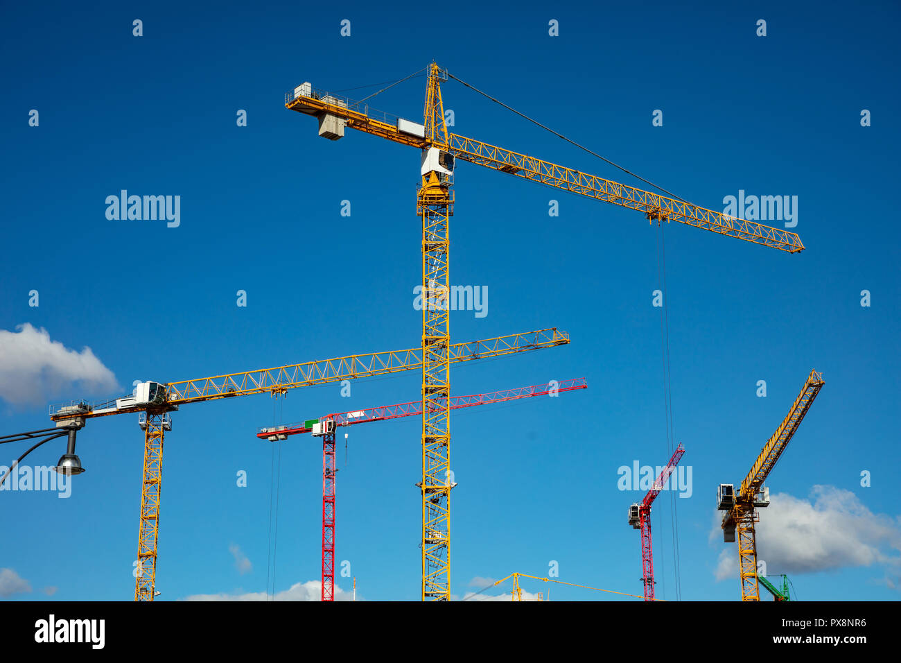 Under construction. Tower cranes on blue sky background Stock Photo - Alamy