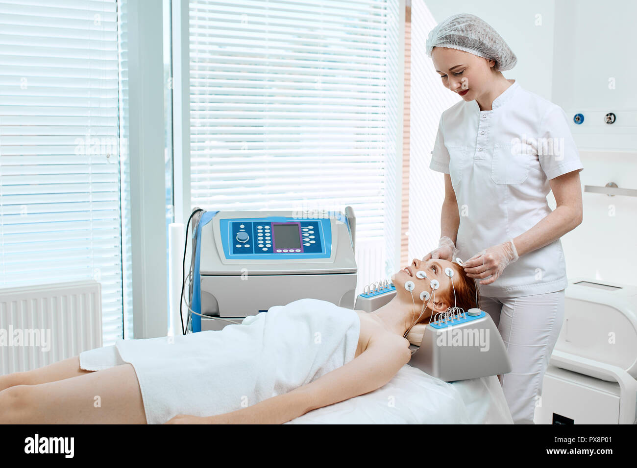 Woman with electrodes on her face, receiving electric stimulation on ...