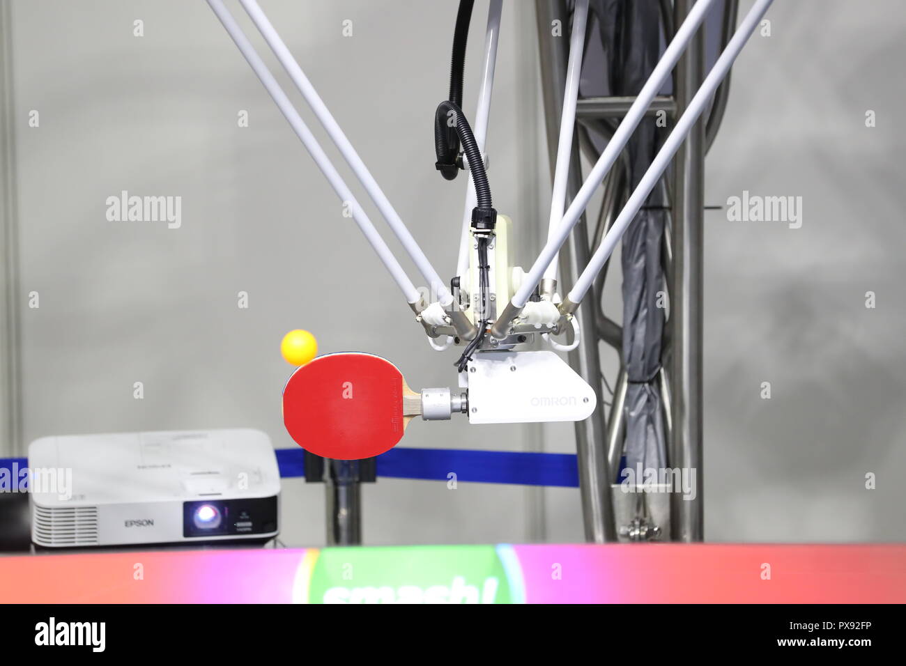 A staff member plays table tennis with Omron Corp.'s table tennis robot ...