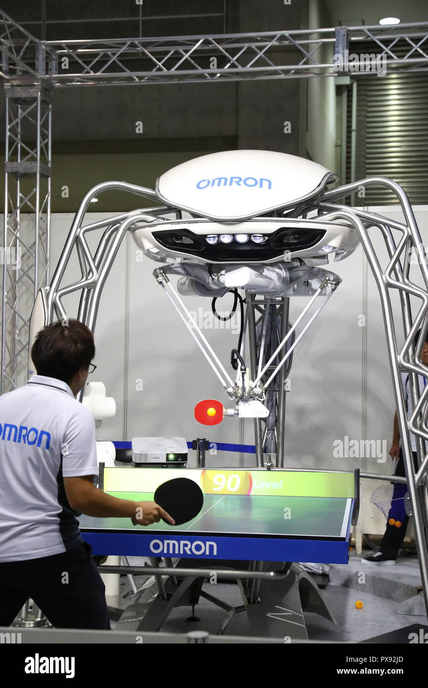 A staff member plays table tennis with Omron Corp.'s table tennis robot ...