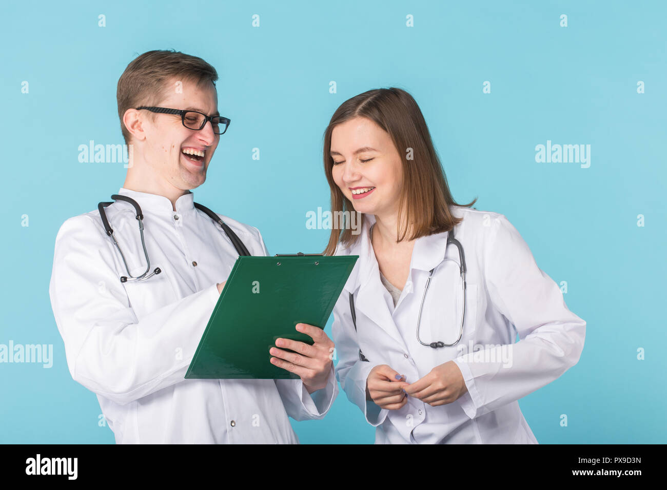 Young male and female doctors are laughing in blue background Stock ...
