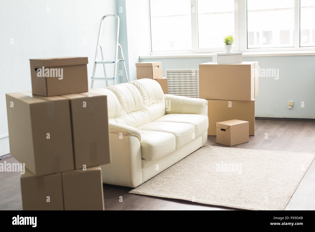 Relocation, new home and real estate concept - Moving boxes and sofa in ...
