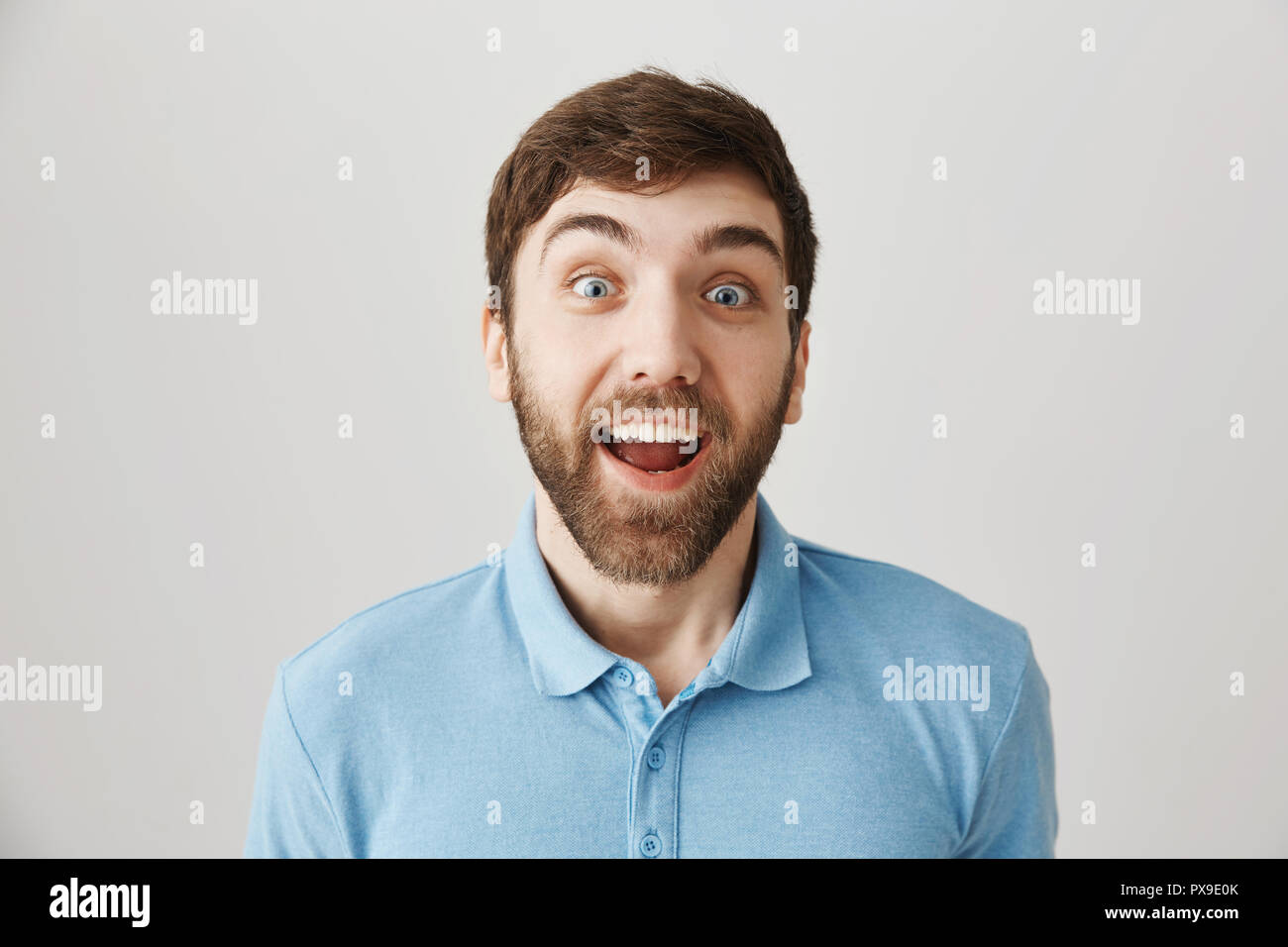 Waist Up Shot Of Funny Emotive Adult Bearded Guy In Blue Polo Shirt
