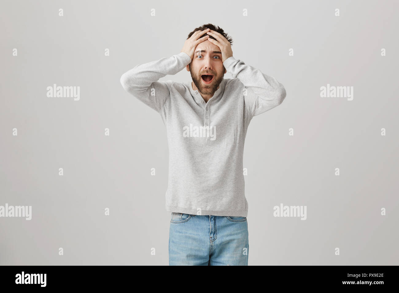 Terrified miserable bearded guy holding hands on hair while shouting ...