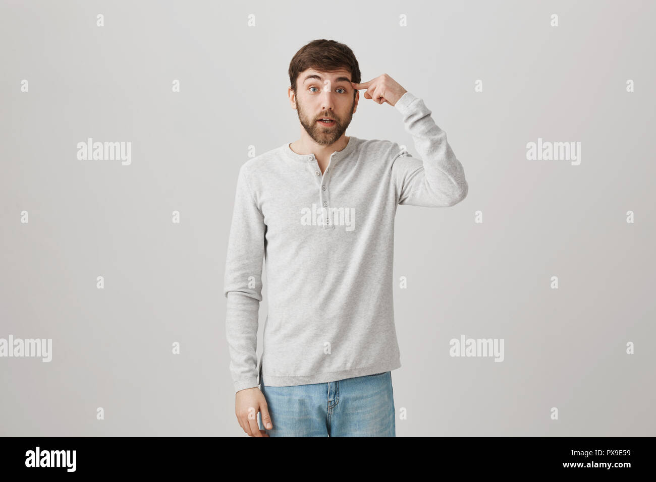 Irritated european male rotating forefinger around temple asking if ...