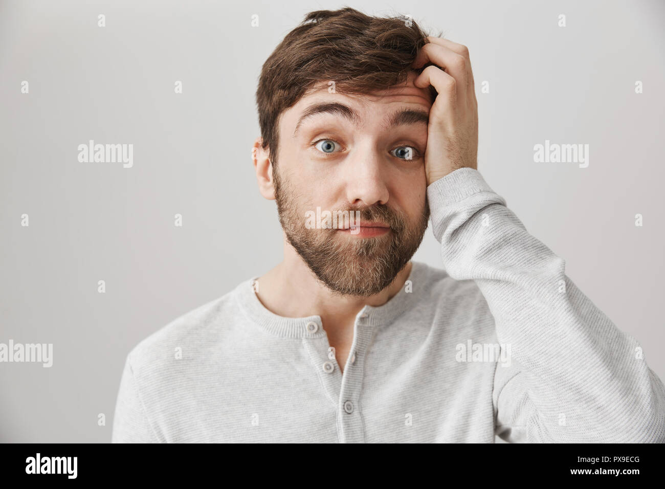 Indoor shot of clueless and puzzled attractive guy with messy beard ...