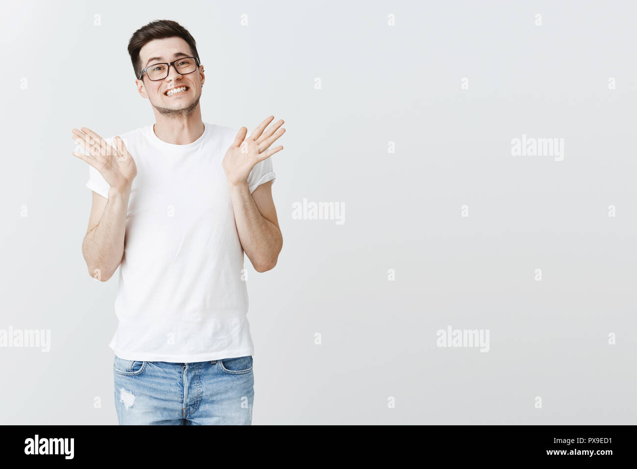 Apologizing handsome young male coworker in glasses raising hands near ...