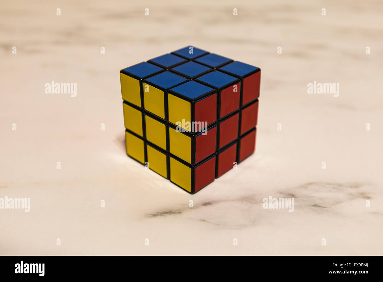Rubik's Cube on a marble plate, showing blue, yellow and red closeup ...