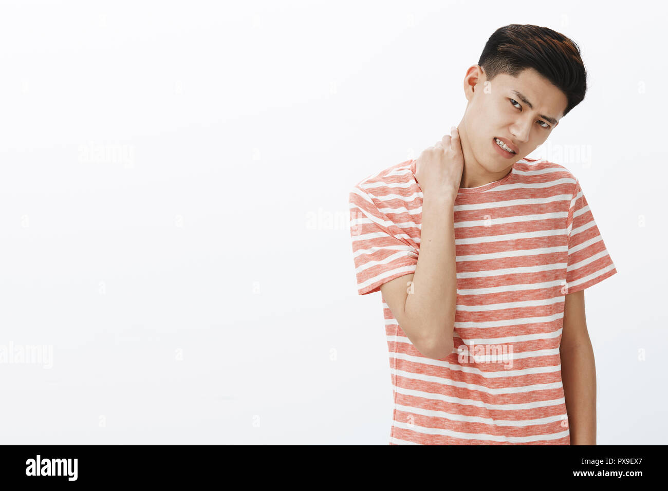 Portrait of bothered uneasy young asian man in striped t-shirt ...