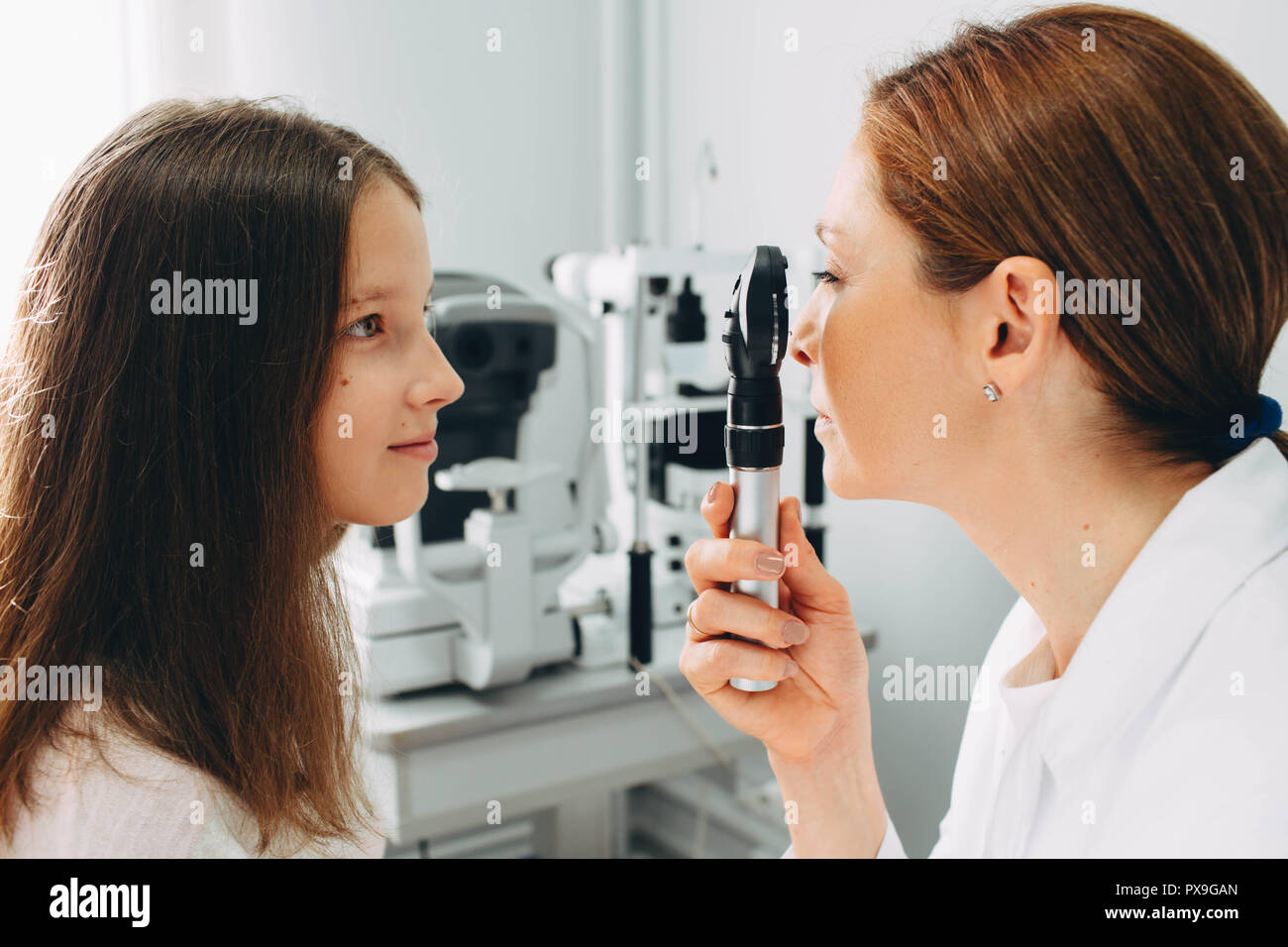 Doctor Optometrist examining teenage girl's eye in doctors office Stock ...
