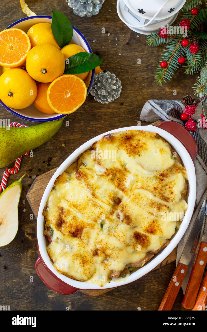 Potato gratin with pear, raclette cheese, and bacon on a festive ...