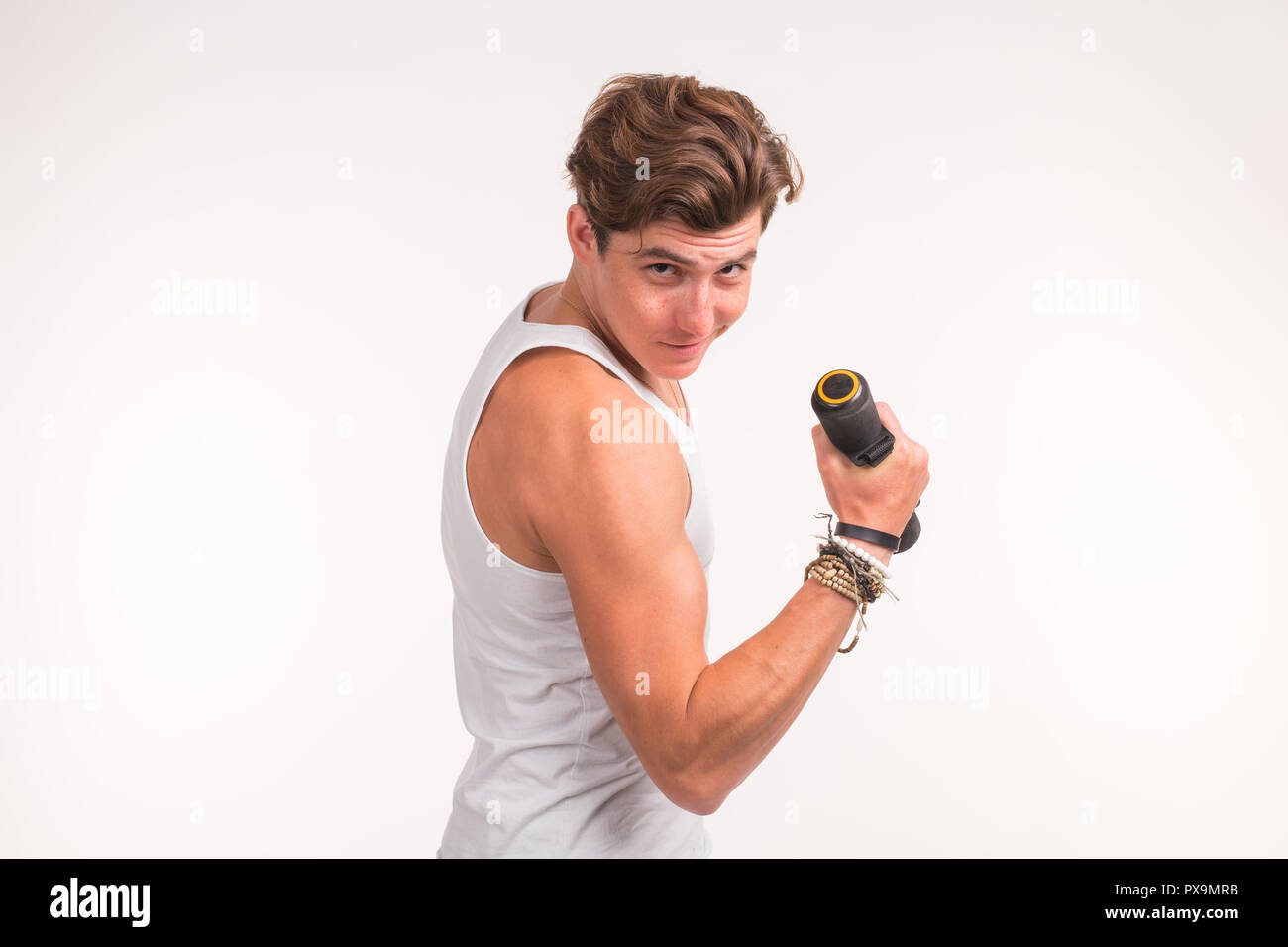 An attractive sporty man shows his biceps and smiling on white ...