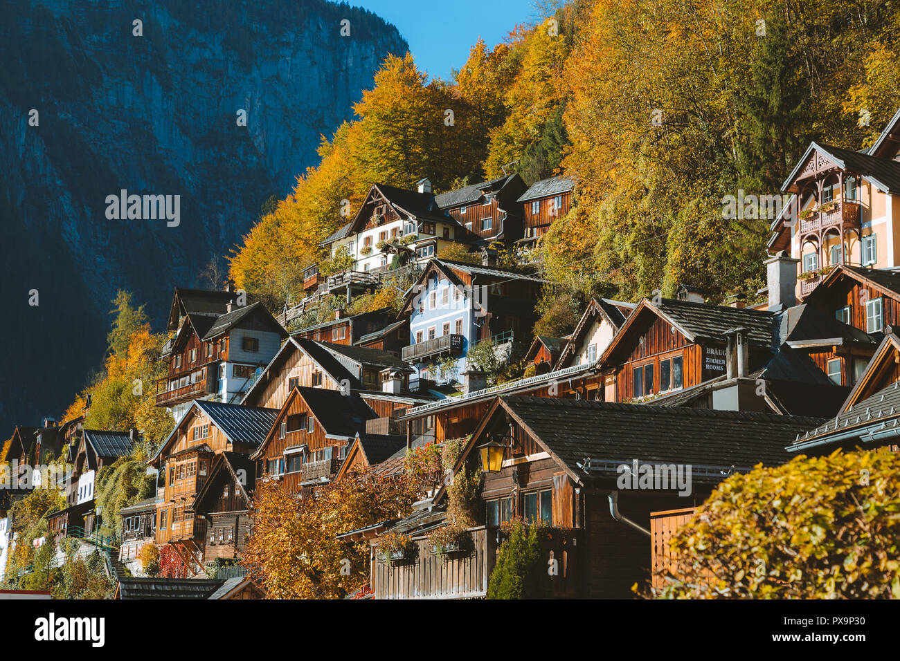 Scenic picture-postcard view of traditional old wooden houses up the hill in famous Hallstatt ...