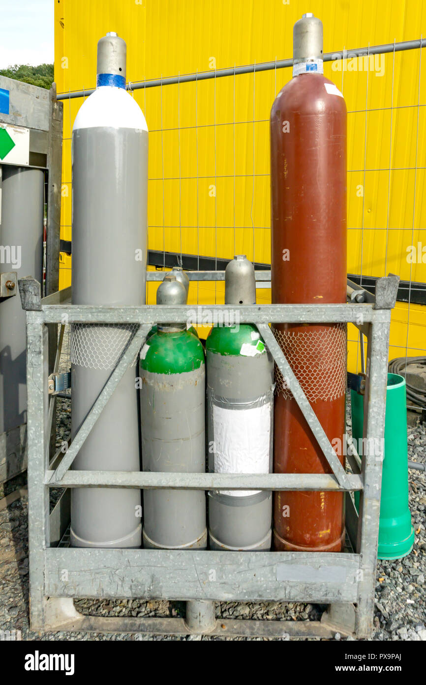 Selection of different gas bottles on a metal stand outdoors on gravel ...