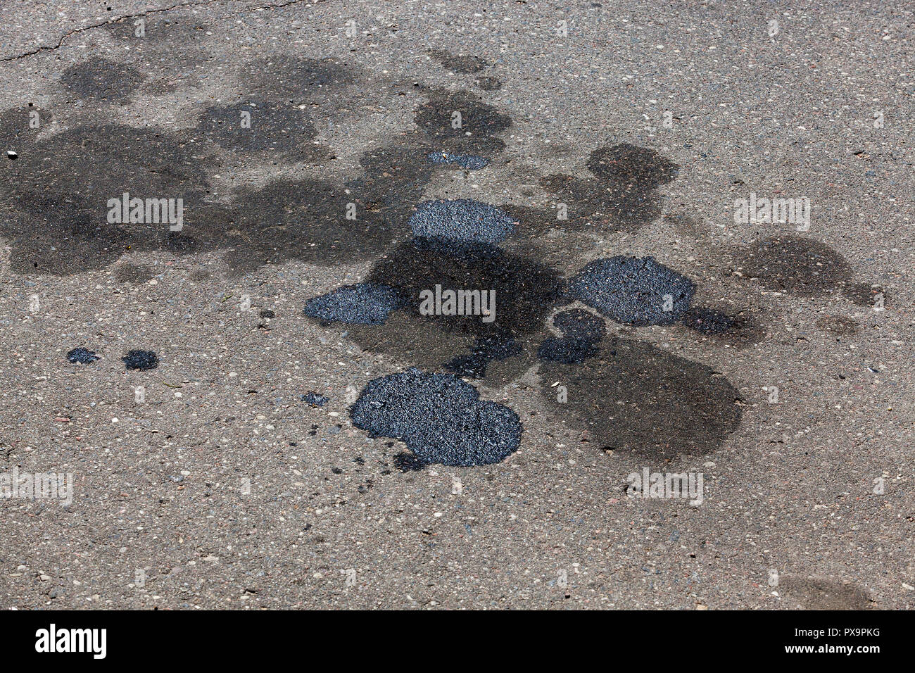 large stains of oil, fuel oil and other emissions from cars on asphalt ...