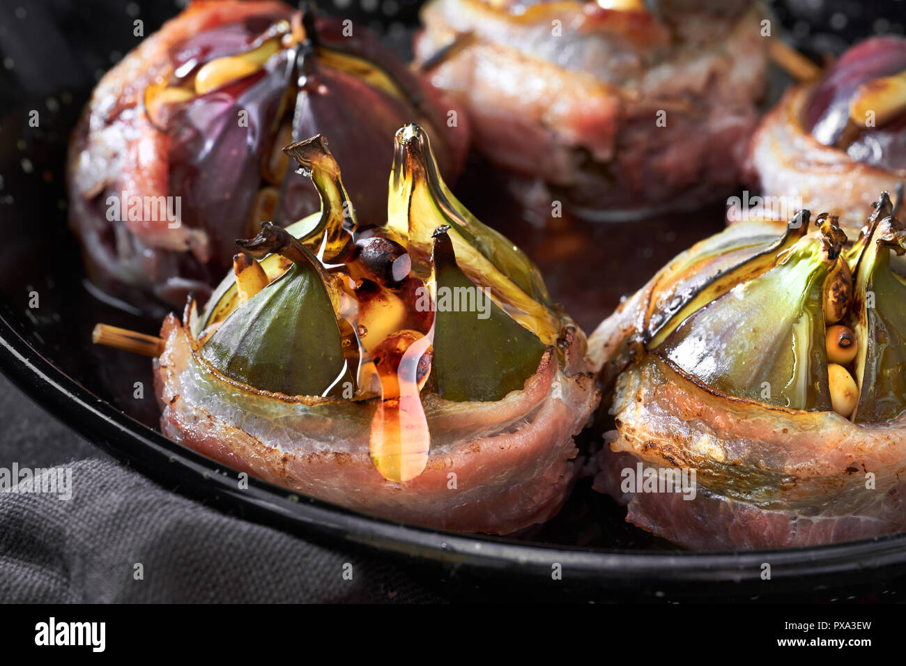 Closeup on baked fig wrapped in bacon, stuffed with pine nuts and ...