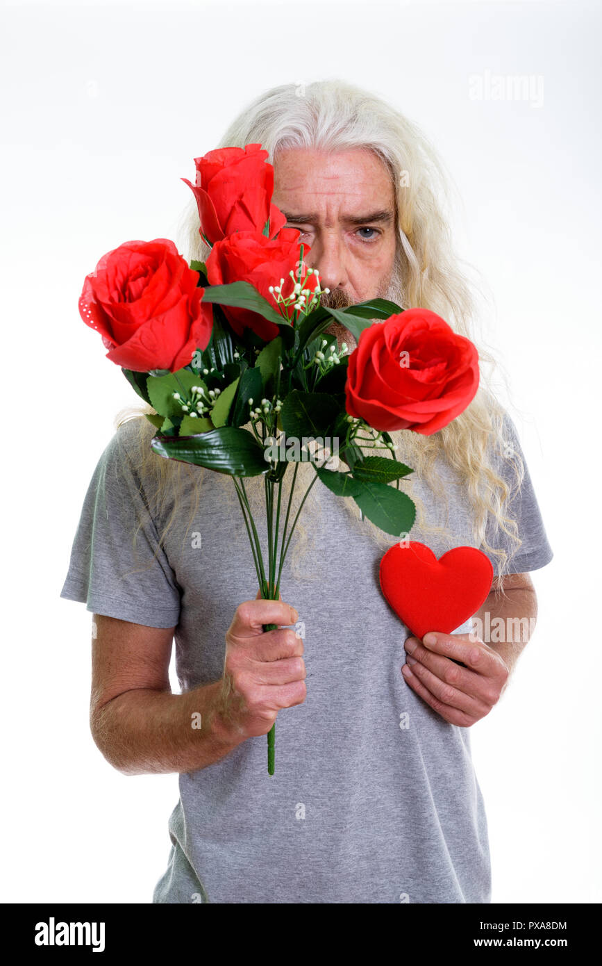 Studio shot of senior bearded man hiding behind red roses while Stock ...