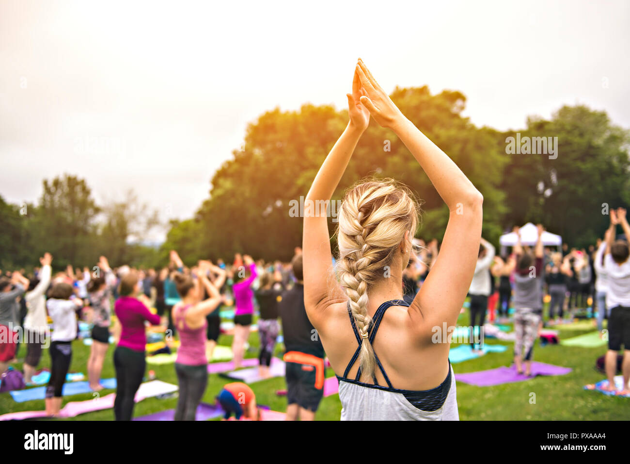 A big group of adults attending a yoga class outside in park Stock ...