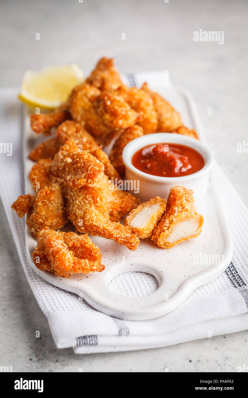Fried chicken with tomato sauce on a white board Stock Photo - Alamy