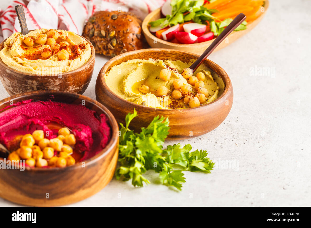 Different hummus bowls. Chickpea hummus, avocado hummus and beet hummus ...
