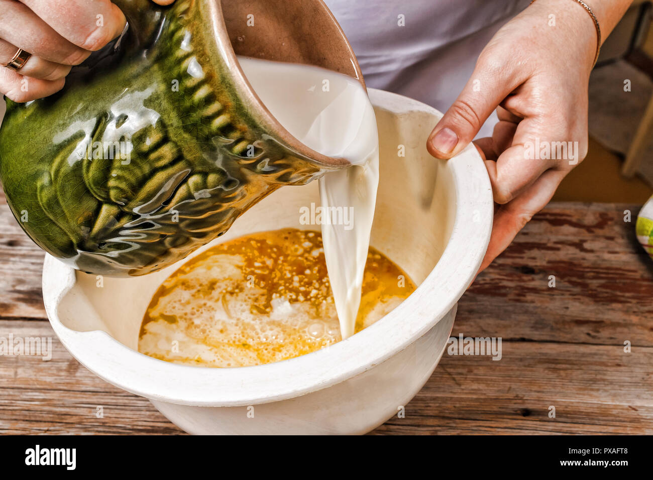 Bakery. Pouring milk into a bowl. Dough preparation. Hands of a baker ...