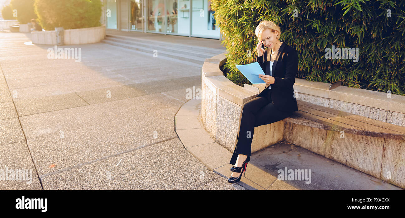 Blonde secretary speaking with boss by smartphone outside in . Concept ...