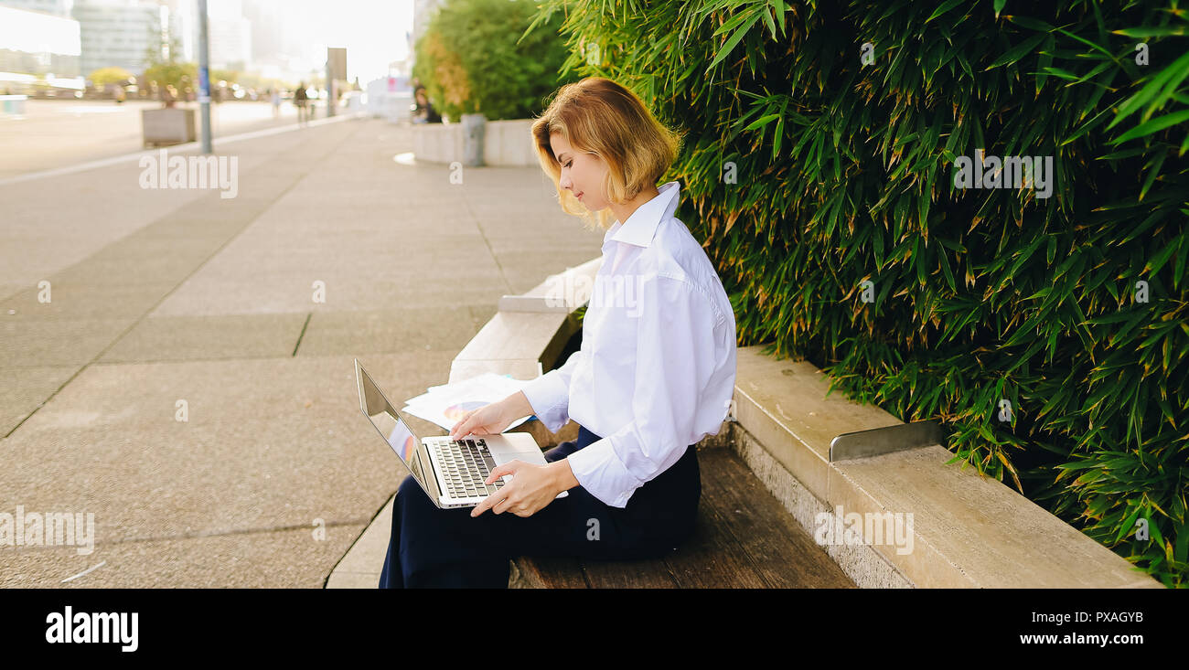 Female statistician working with color diagrams and laptop outdoors ...