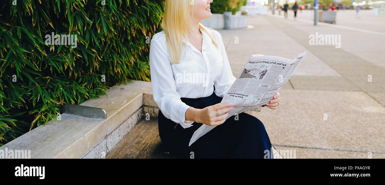 Female person reading newspaper article outside in with close up face ...