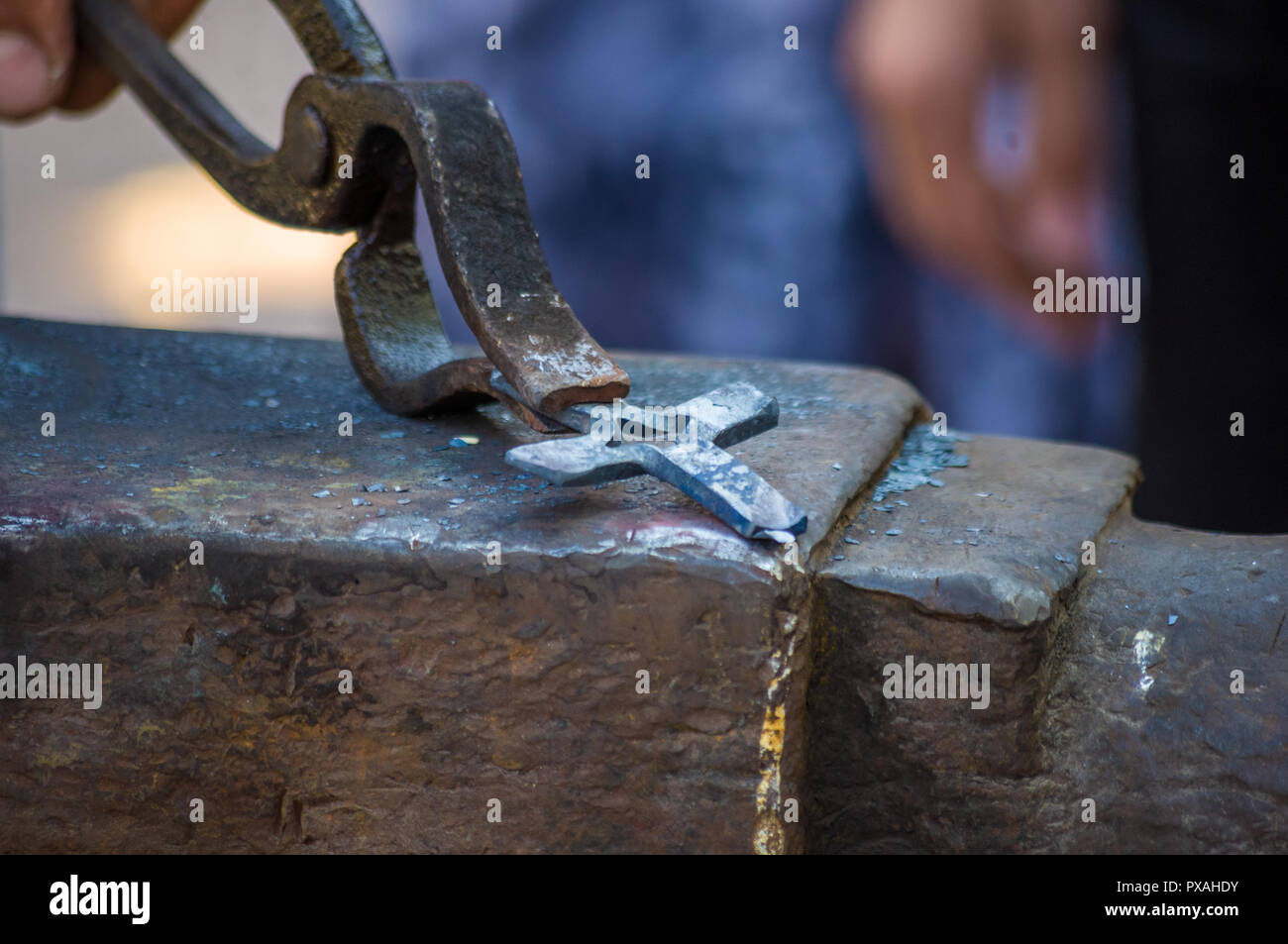 blacksmith performs the forging of hot glowing metal on the anvil ...