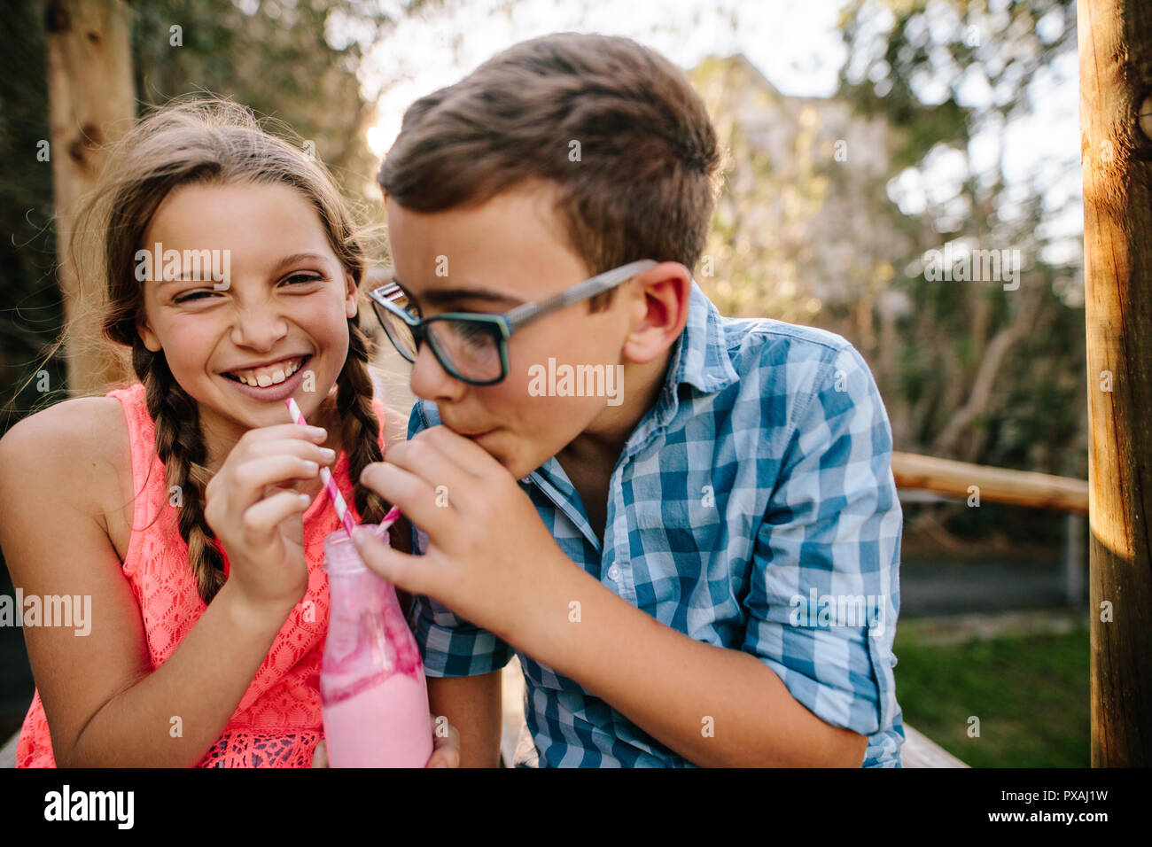 Close up of a smiling boy and girl drinking milk shake using two straws ...